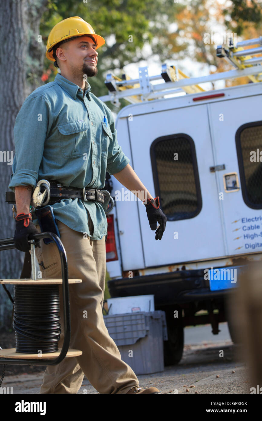 Cable lineman bringing reel of cable to site Stock Photo - Alamy