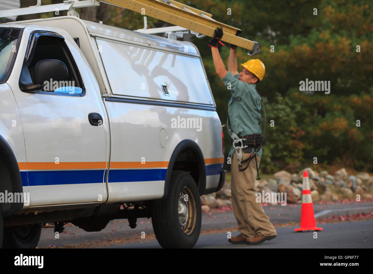 Lineman putting ladder back on truck at site Stock Photo - Alamy