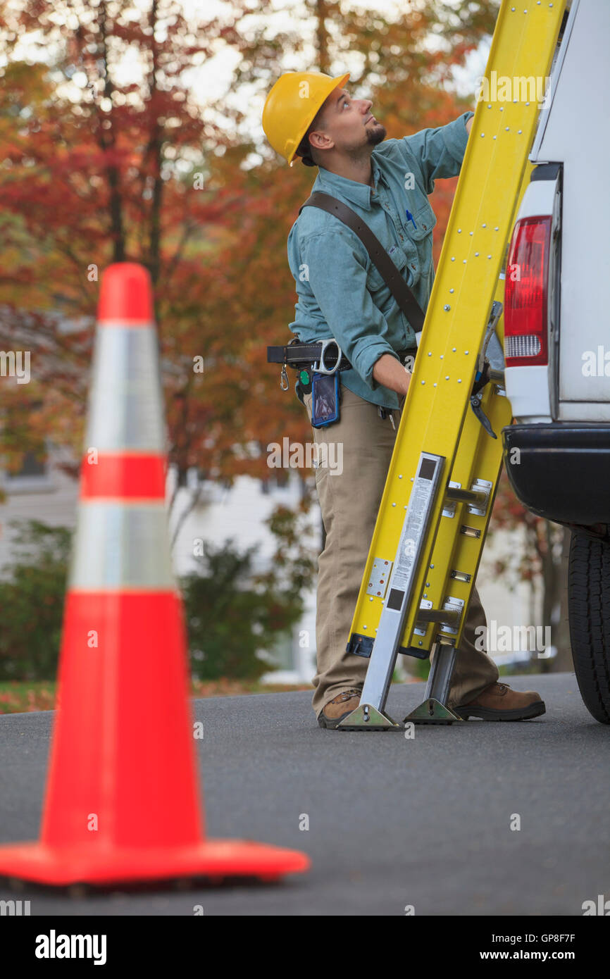 Lineman with ladder on truck at site Stock Photo - Alamy