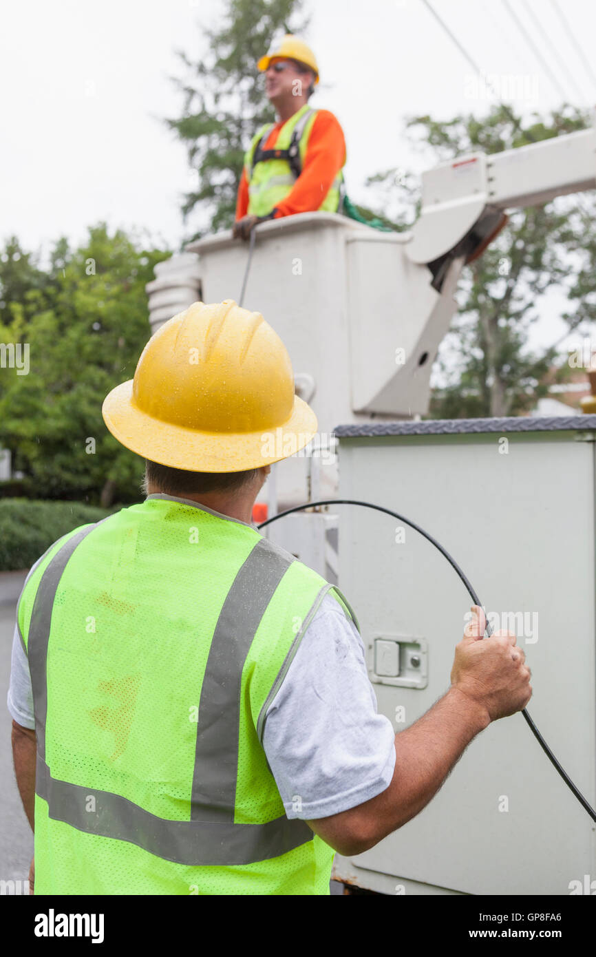 Utility workers preparing to work on power lines in a bucket truck ...
