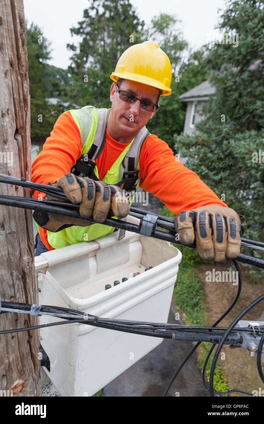 Cable lineman securing cable to pole from a bucket truck Stock Photo ...