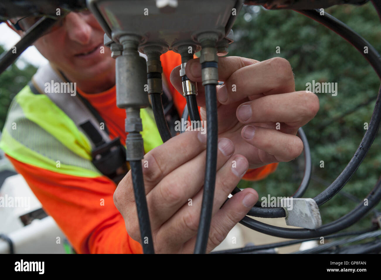 Cable lineman attaching new cable to junction box from a bucket truck ...