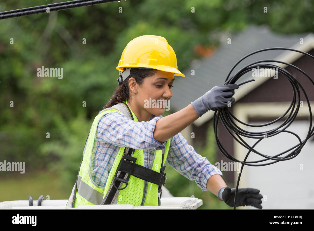 Hispanic female cable lineman stringing a new line in the rain Stock ...
