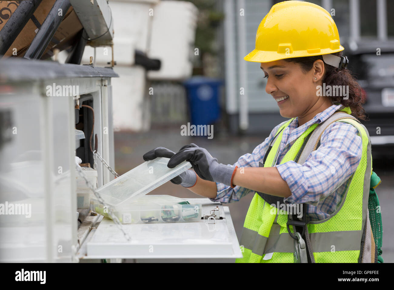 Hispanic female utility worker with box of cable amplifiers at site ...