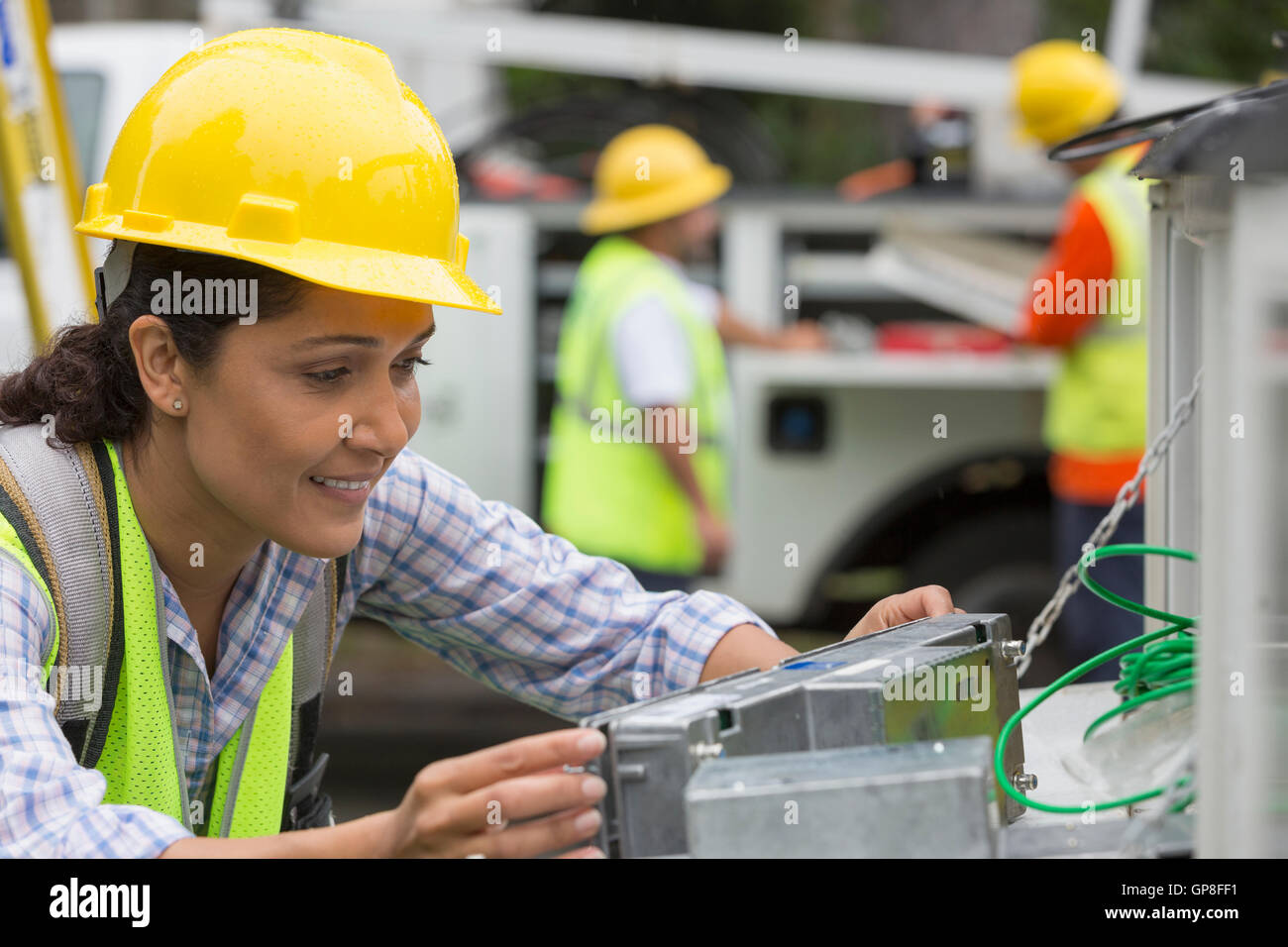 Hispanic female utility worker working with line amplifiers at site ...
