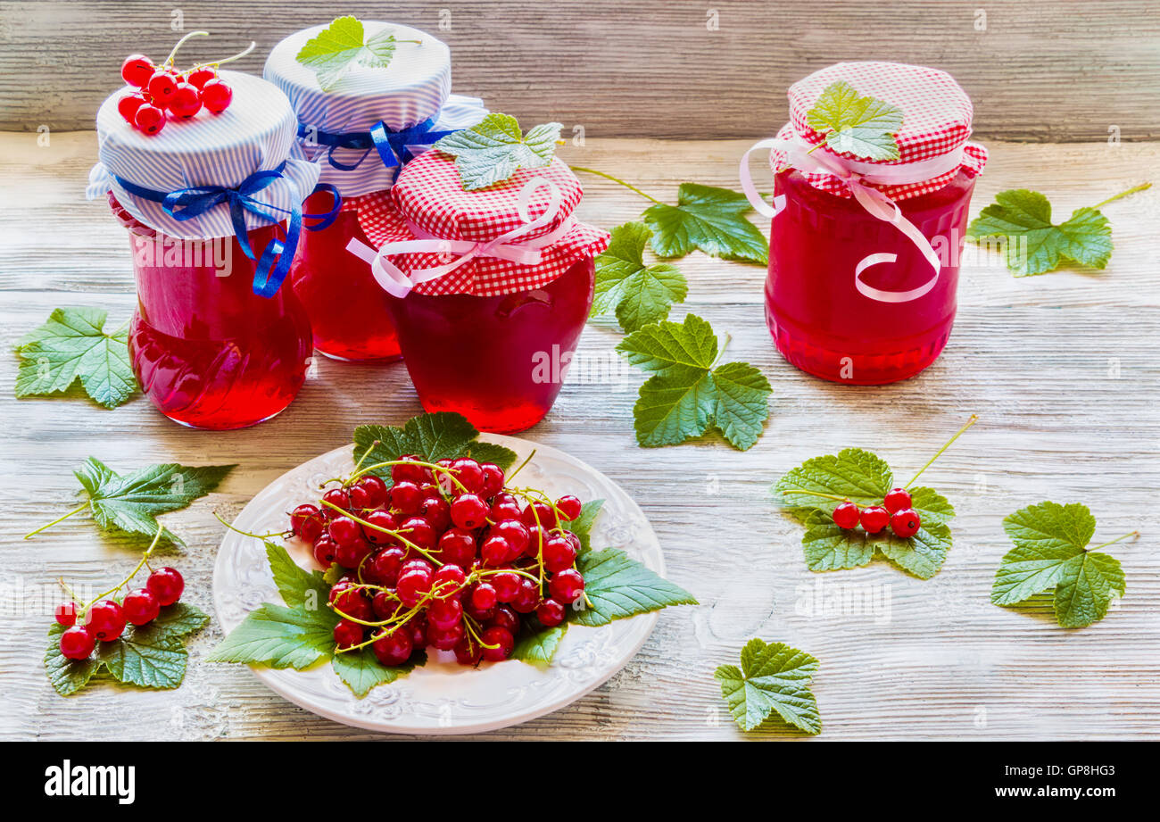 Preserved homemade red currant jam in glass jars on white wooden table ...