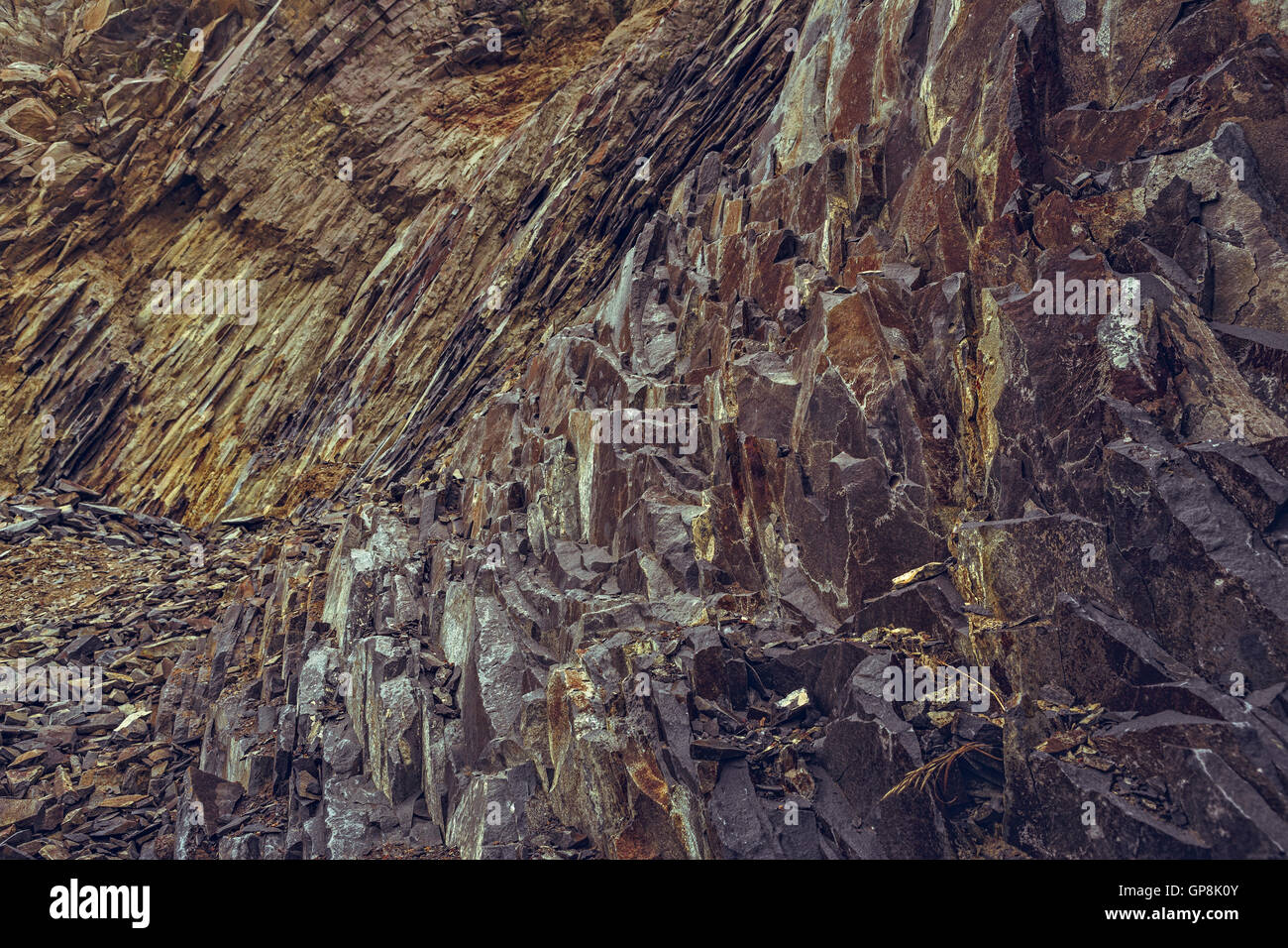 Arid strata volcanic rock cliff and stone debris in an old abandoned ...