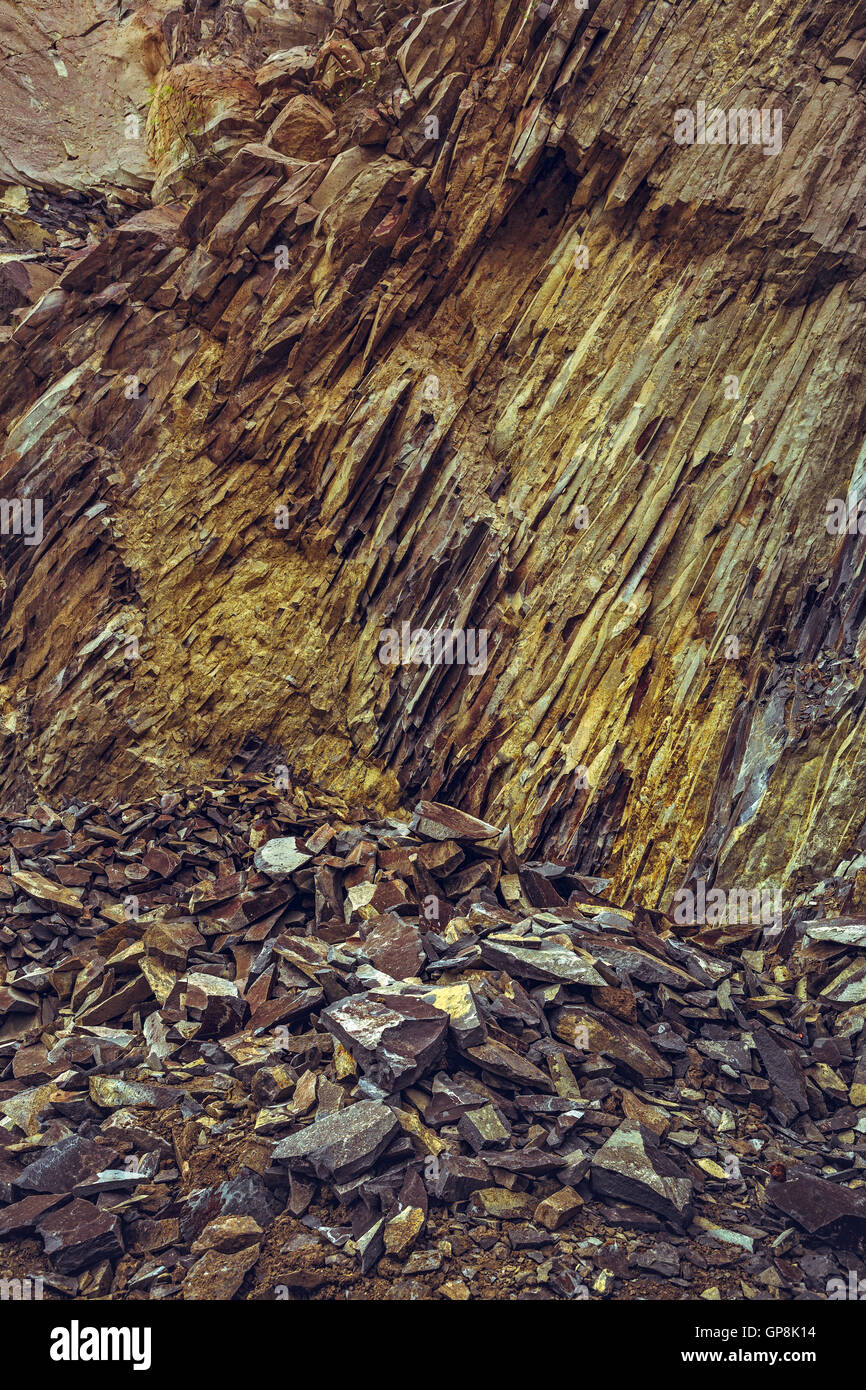 Arid layered rock wall and debris in a deserted basalt quarry in Racos ...