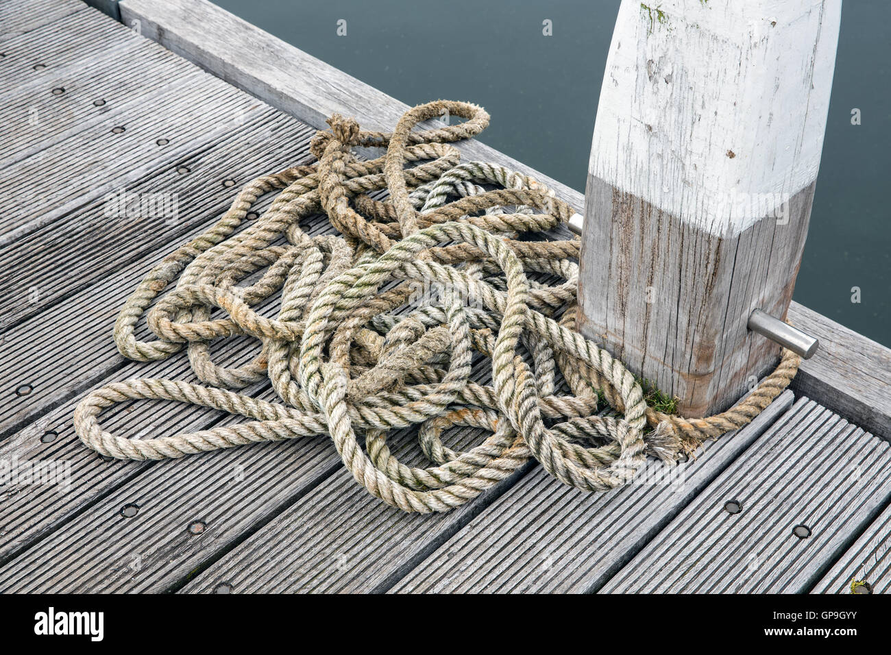 Wooden pier with bollard and rope Stock Photo - Alamy
