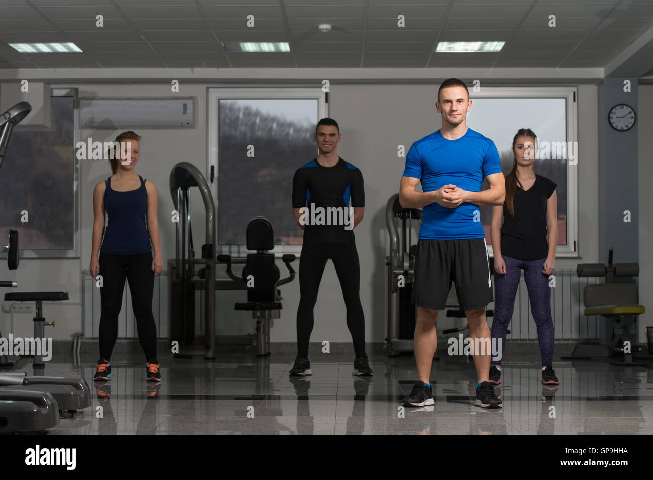 Group Of Young People Stretching In Gym For Better Fitness Led By ...
