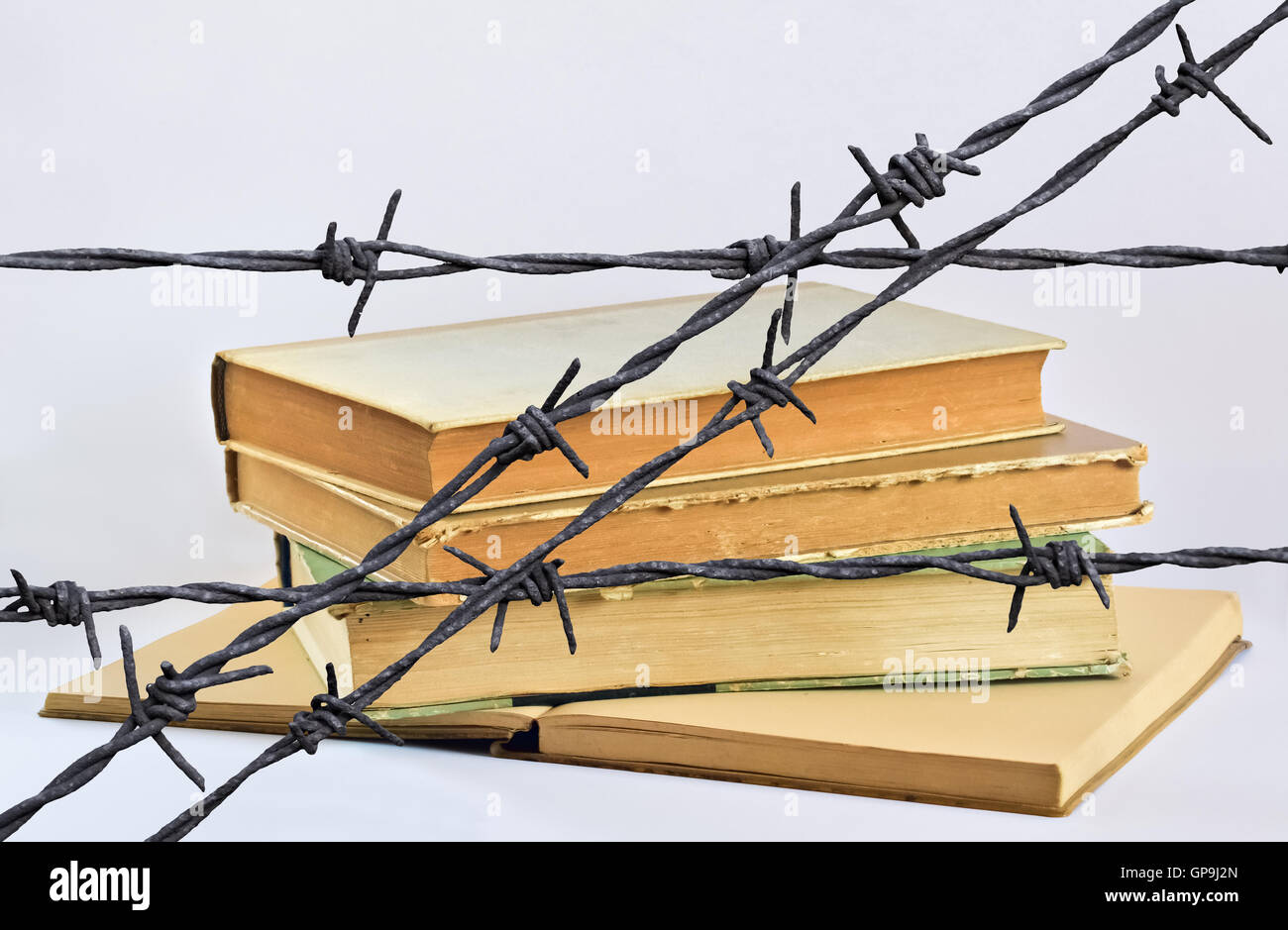 Stack of several old books behind a wire with barbs Stock Photo - Alamy
