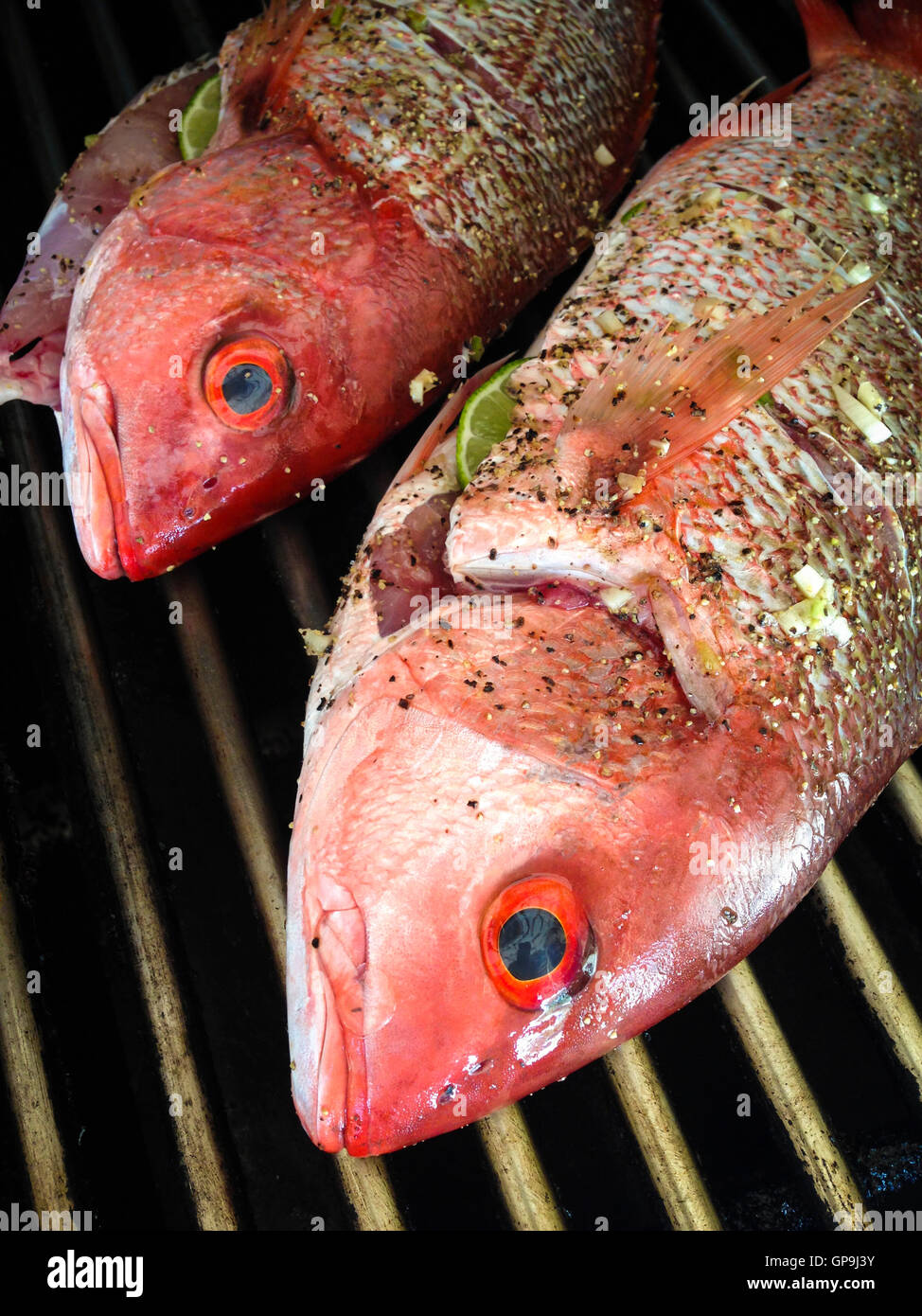Close up of two red snapper fish, stuffed with a slice of lime and ...