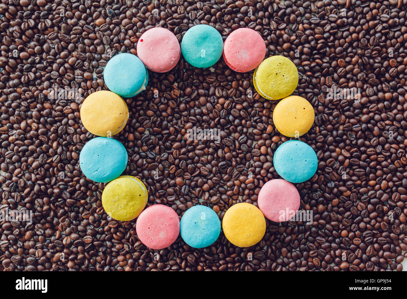 French macaroons laid out in a circle shape on coffee beans background ...