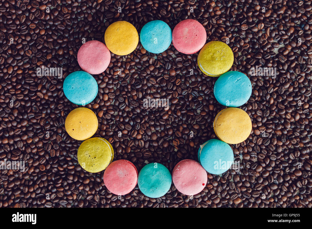 French macaroons laid out in a circle shape on coffee beans background ...