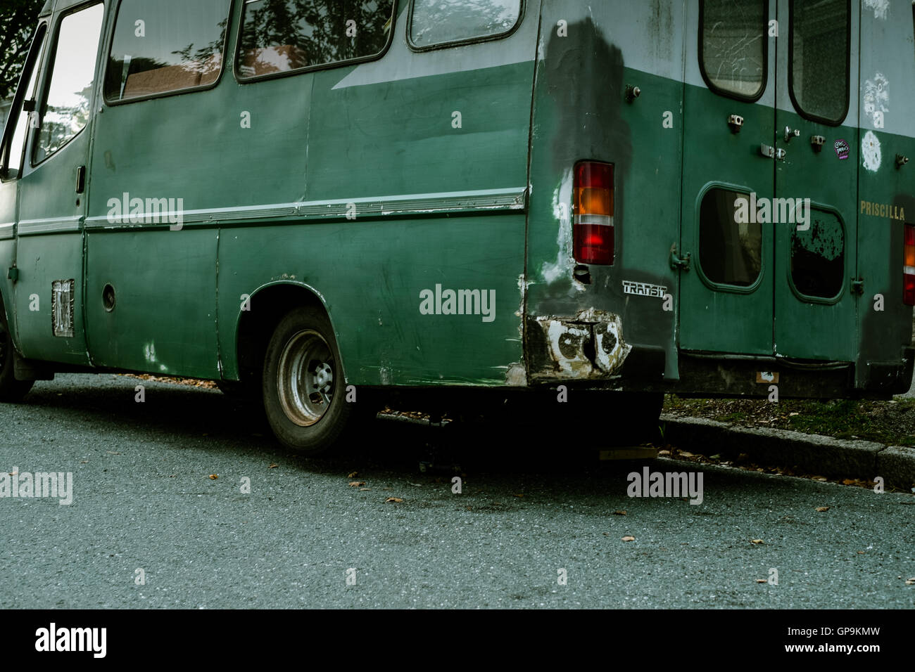 Green long wheelbase Ford Transit van jacked up on side of road for ...