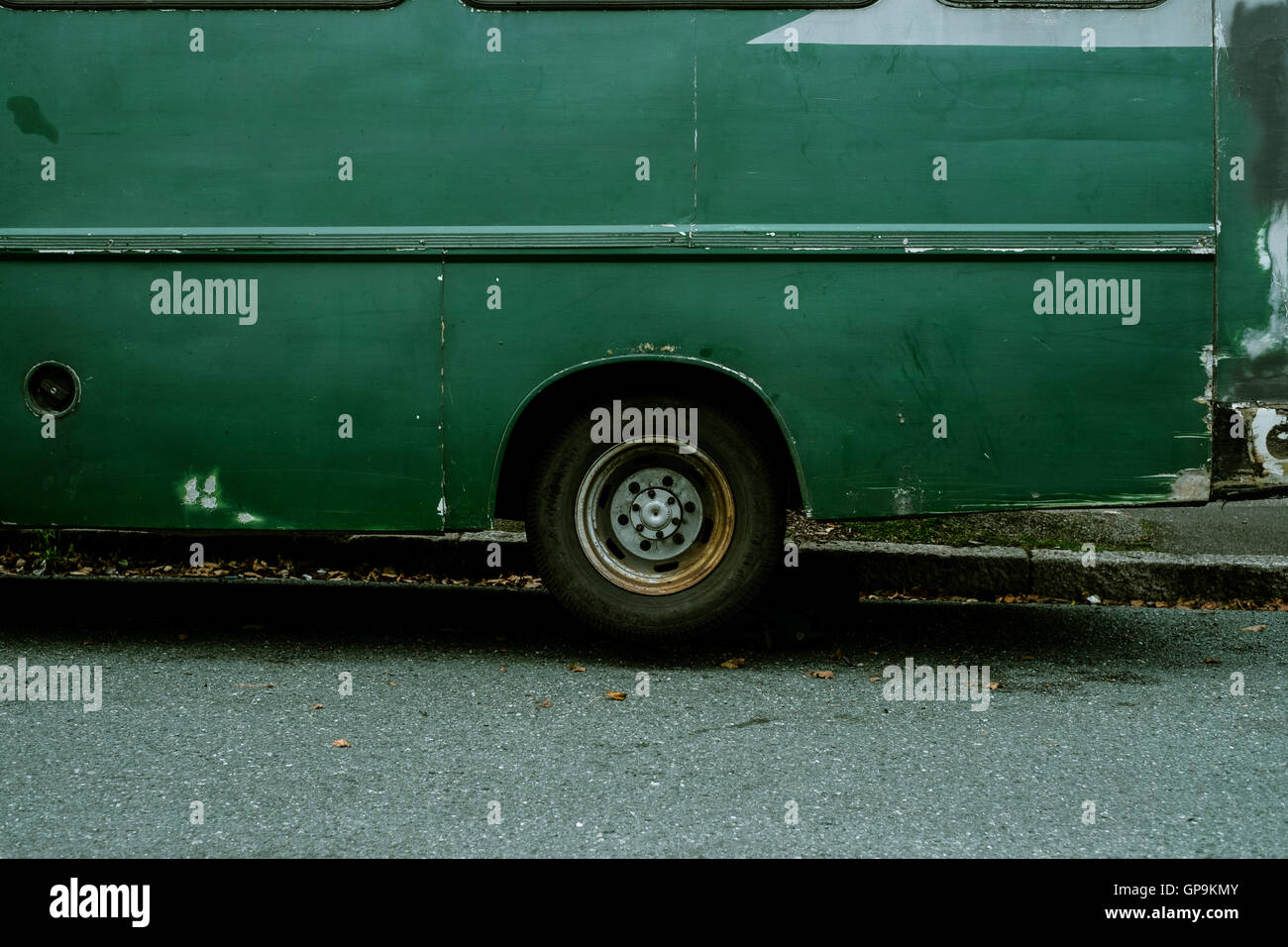Green long wheelbase Ford Transit van jacked up on side of road for ...
