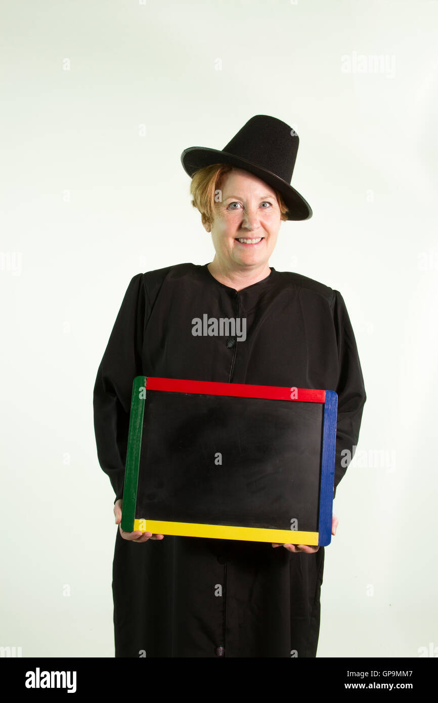 Mature woman dressed in black pilgrim robe and hat holding chalkboard ...