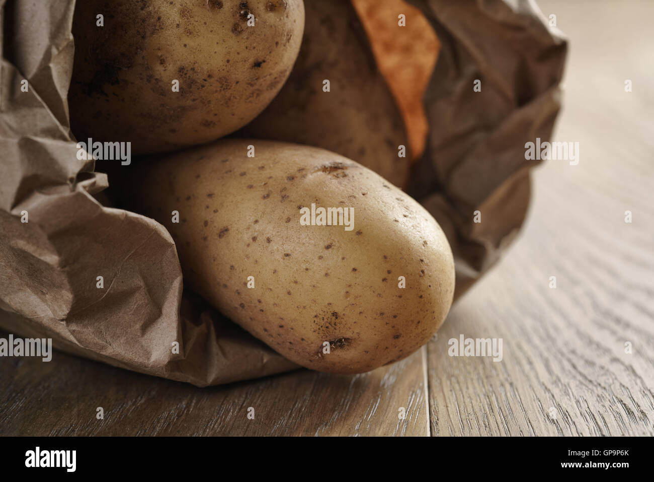 fresh potatoes in kraft paper bag on oak table Stock Photo - Alamy
