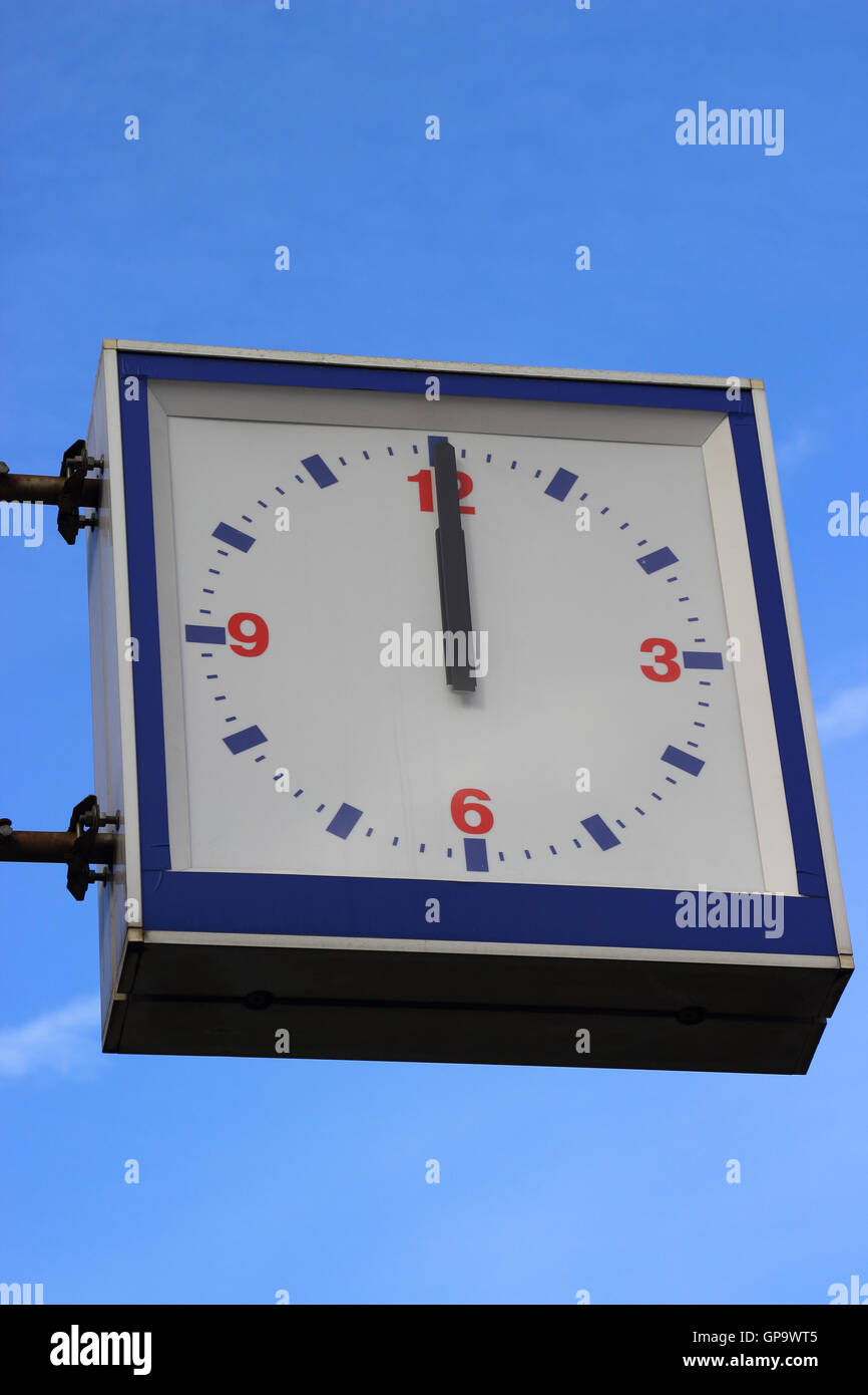 Street clock showing noon on blue sky background Stock Photo - Alamy
