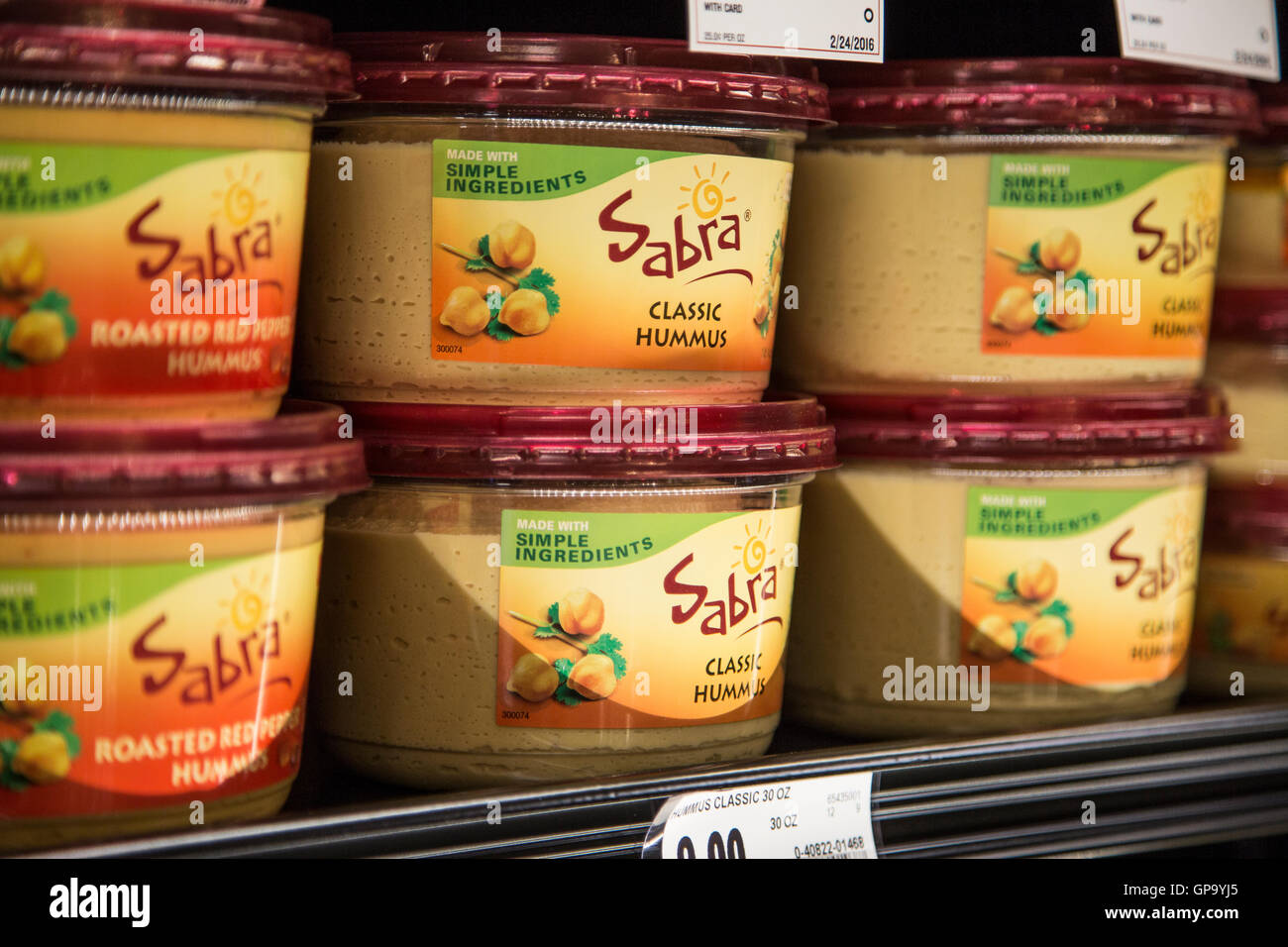 Containers of Sabra brand hummus stacked on a shelf at a grocery store ...