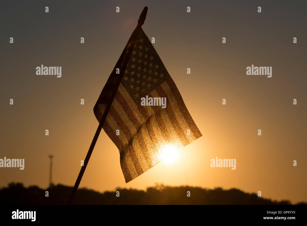 The sun rises behind an American Flag flying outside a cabin near ...