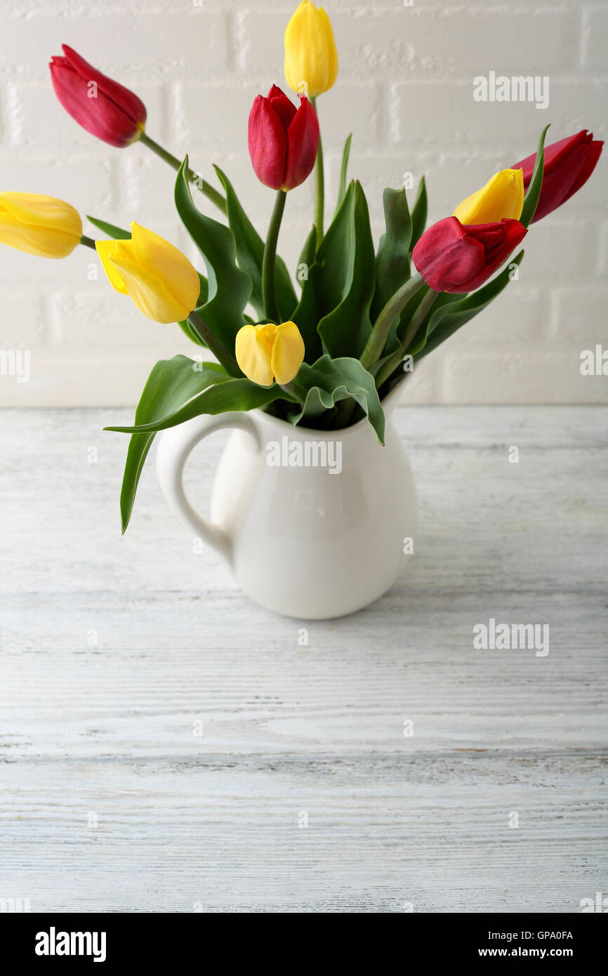 Spring flowers in white pitcher on wood Stock Photo - Alamy