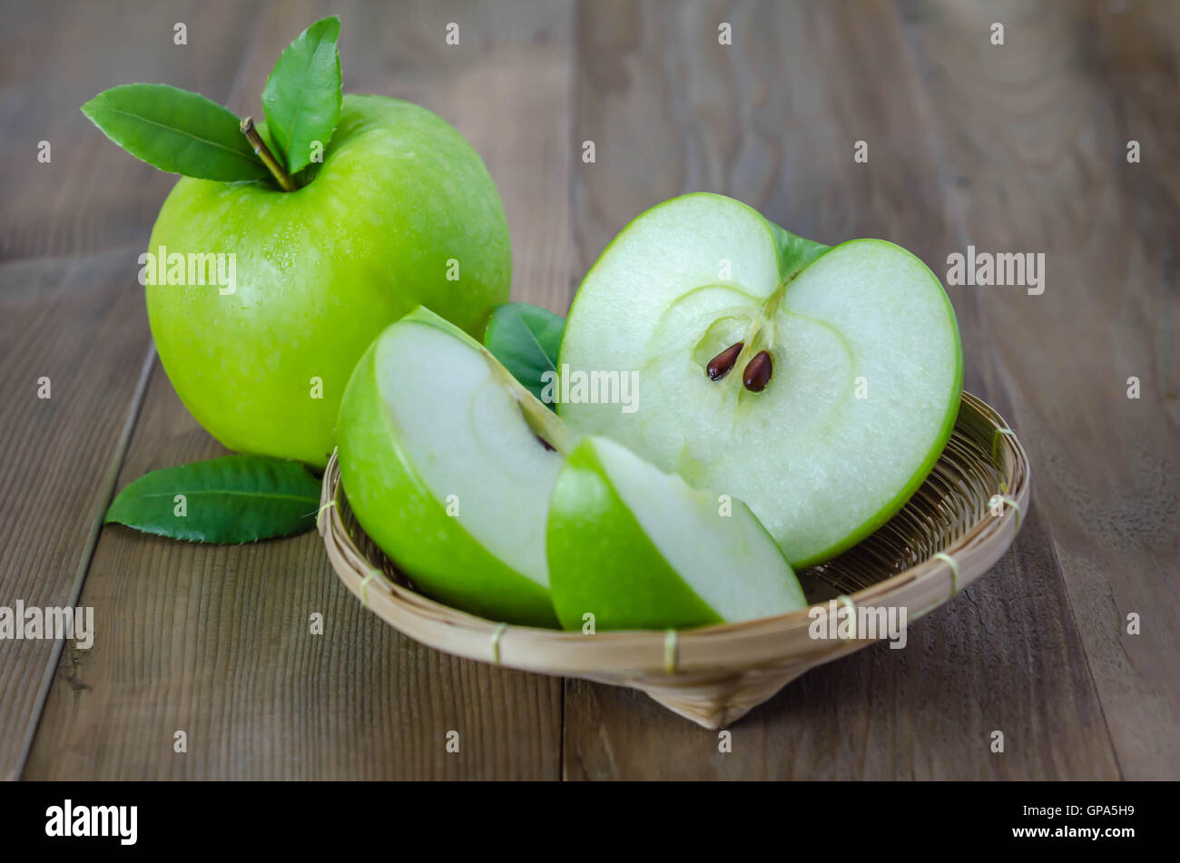Ripe green apple with leaf and slice on a wooden background Stock Photo ...