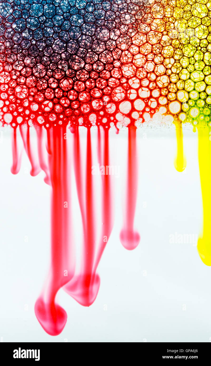 Red, blue and yellow dye flowing through bubbles and water along glass ...