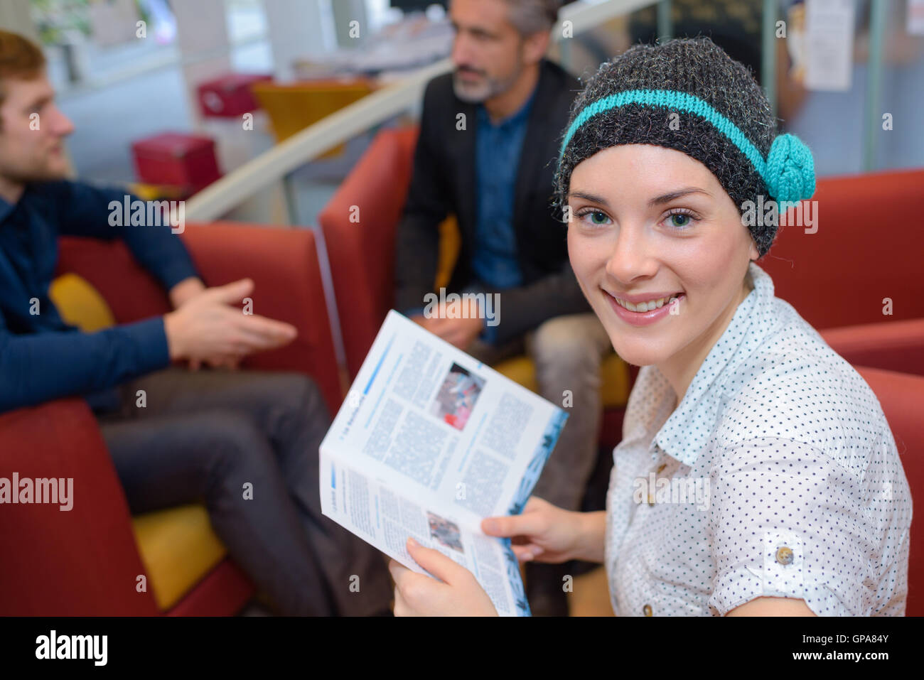 Woman in woolly hat reading brochure Stock Photo - Alamy