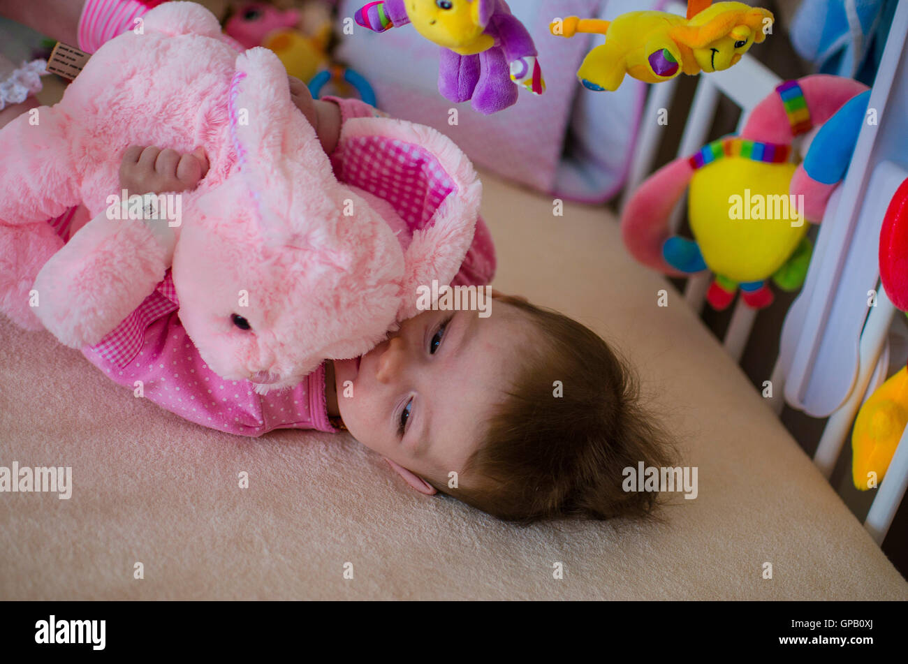 little cute baby girl playing in a cot Stock Photo - Alamy
