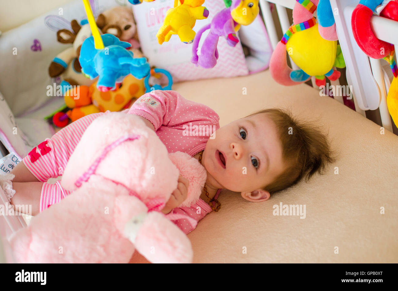 little cute baby girl playing in a cot Stock Photo - Alamy