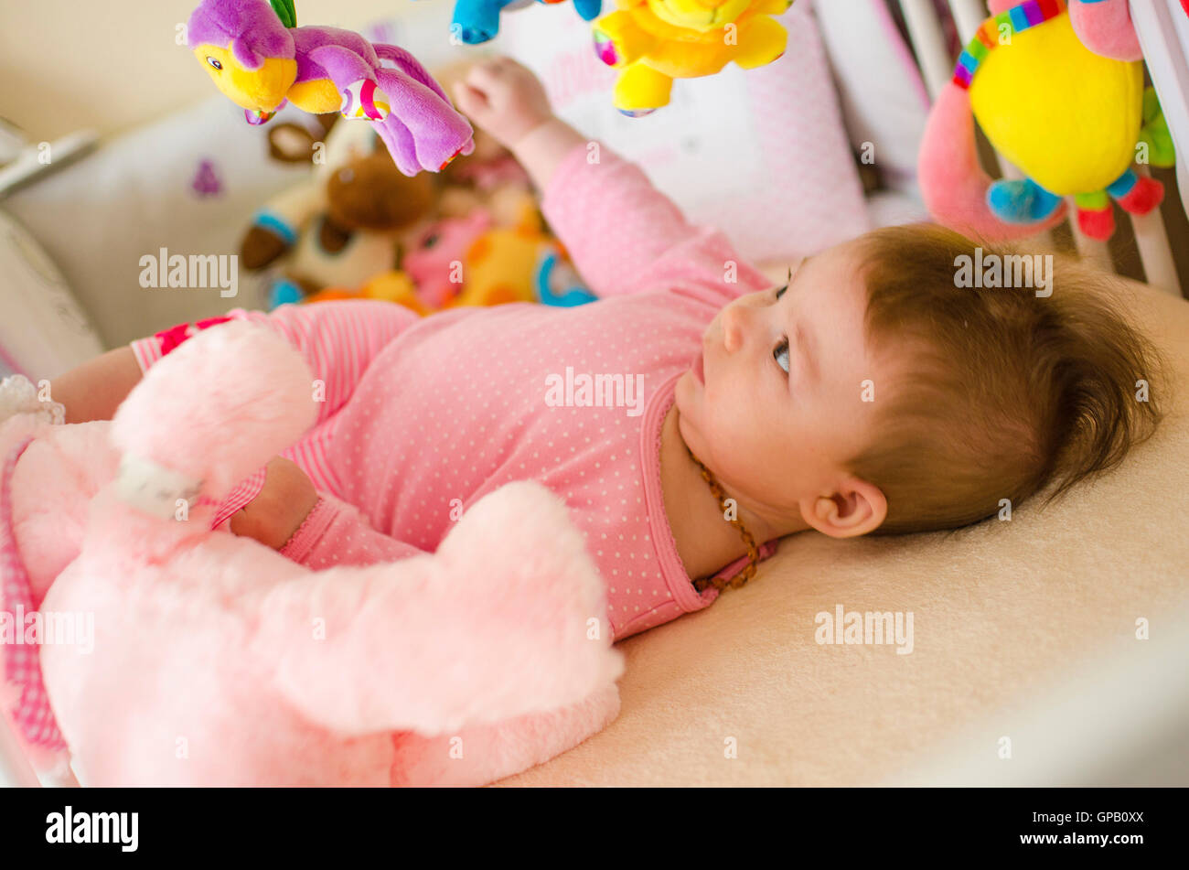 little cute baby girl playing in a cot Stock Photo - Alamy