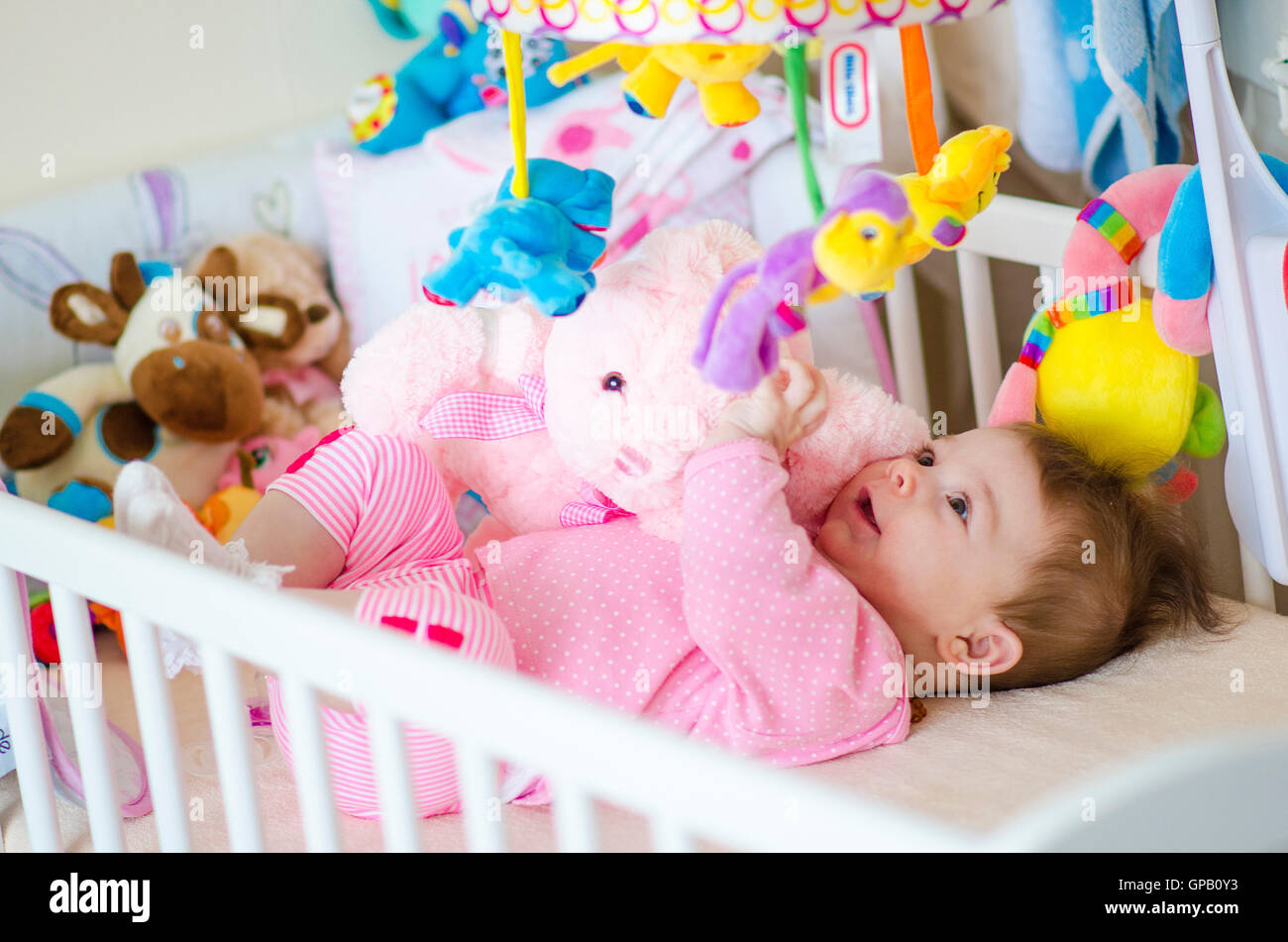 little cute baby girl playing in a cot Stock Photo - Alamy