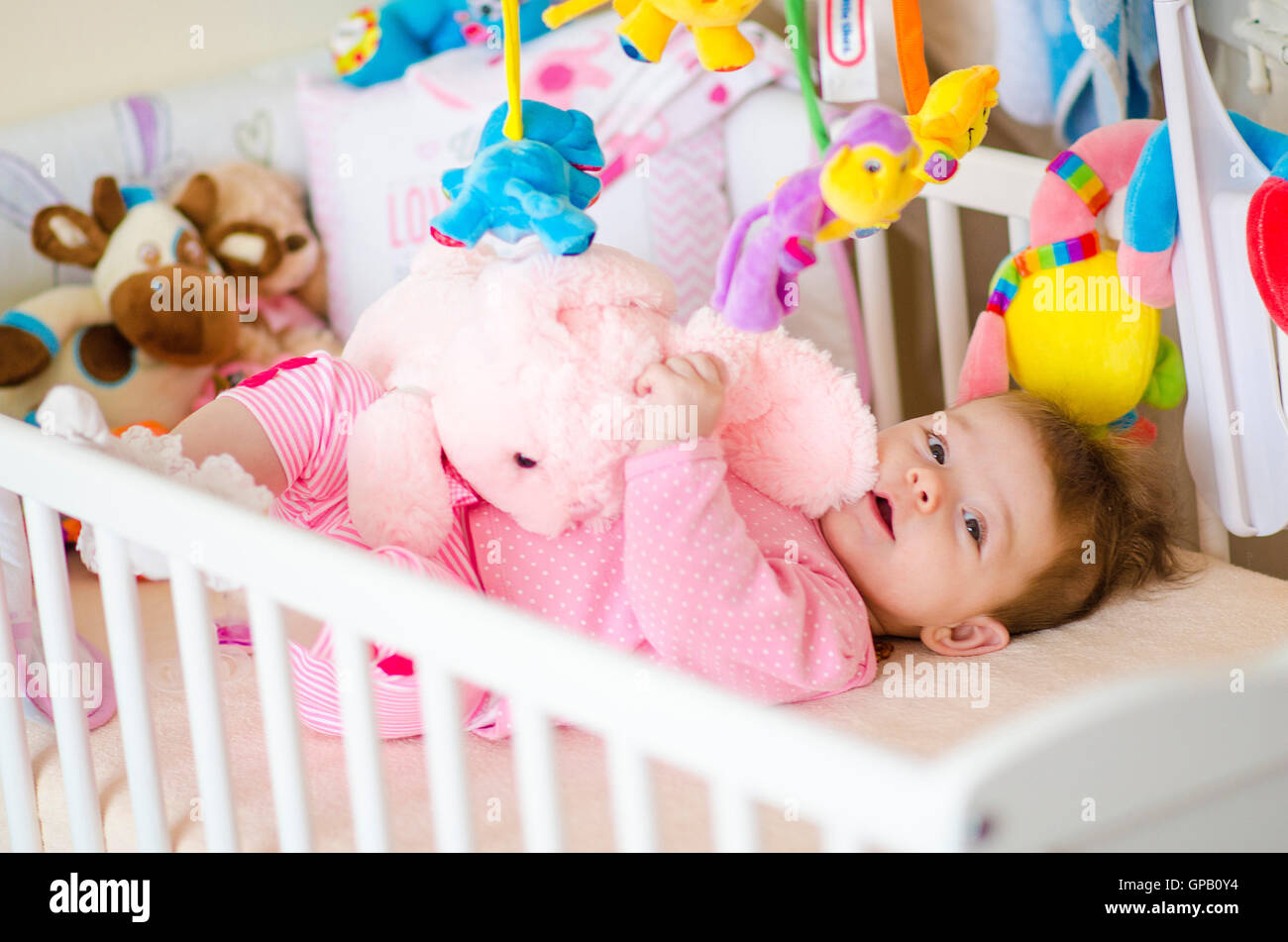 little cute baby girl playing in a cot Stock Photo - Alamy