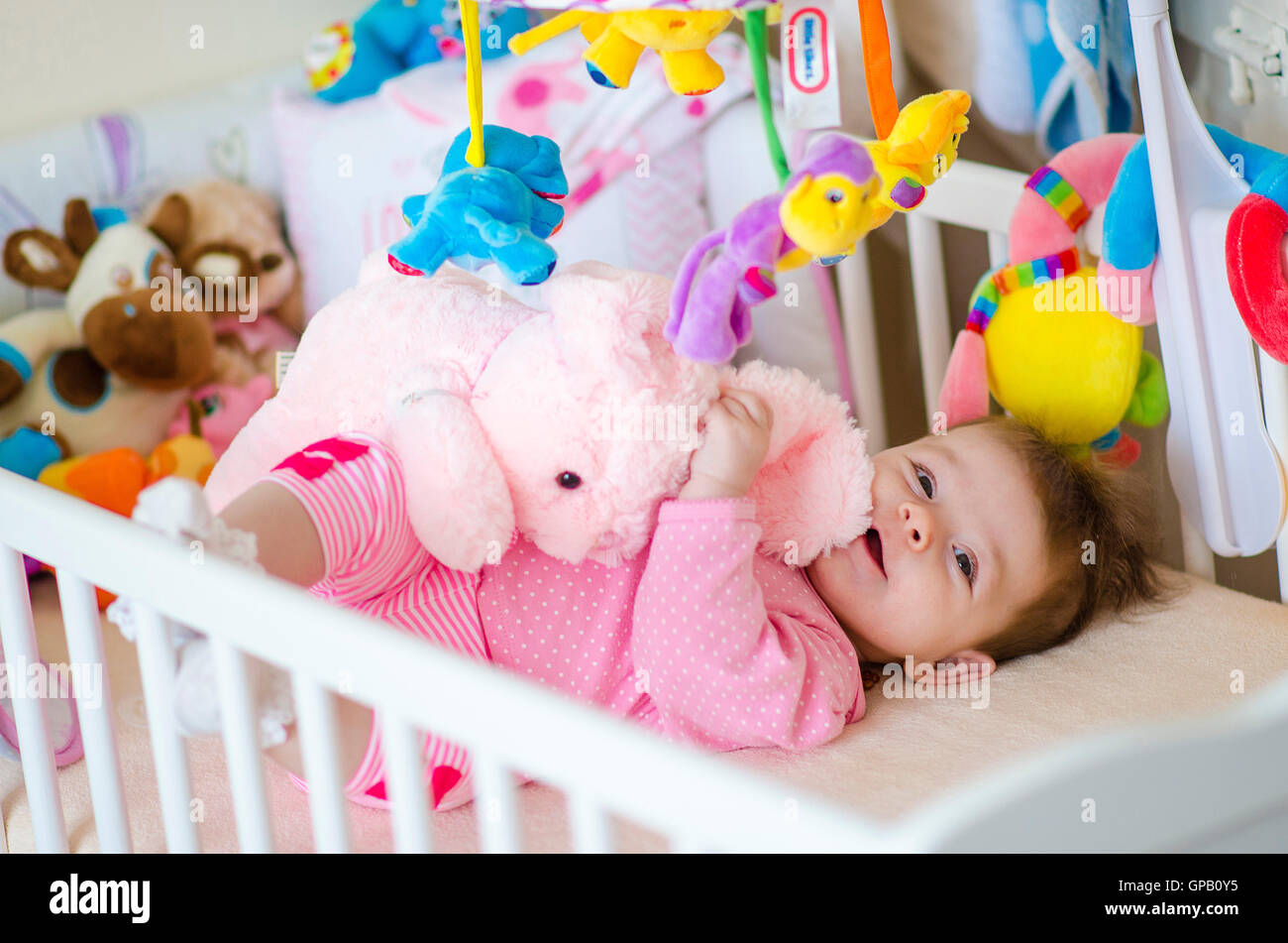 little cute baby girl playing in a cot Stock Photo - Alamy