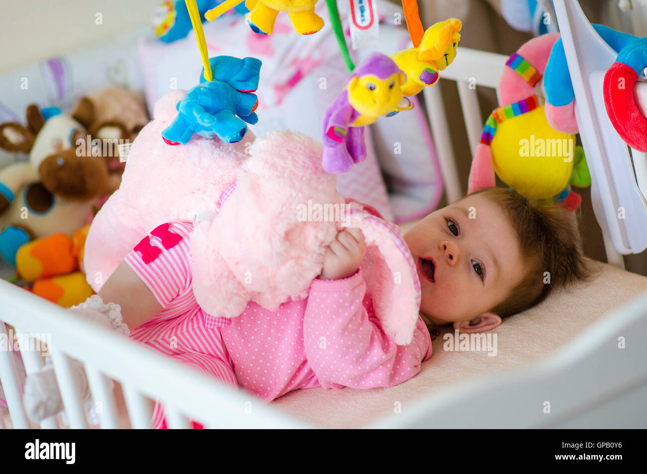 little cute baby girl playing in a cot Stock Photo - Alamy