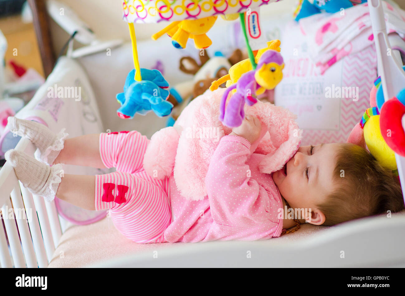 little cute baby girl playing in a cot Stock Photo - Alamy