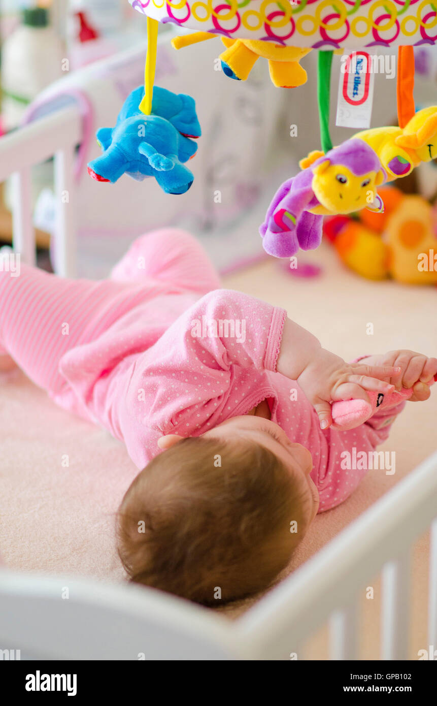 little cute baby girl playing in a cot Stock Photo - Alamy