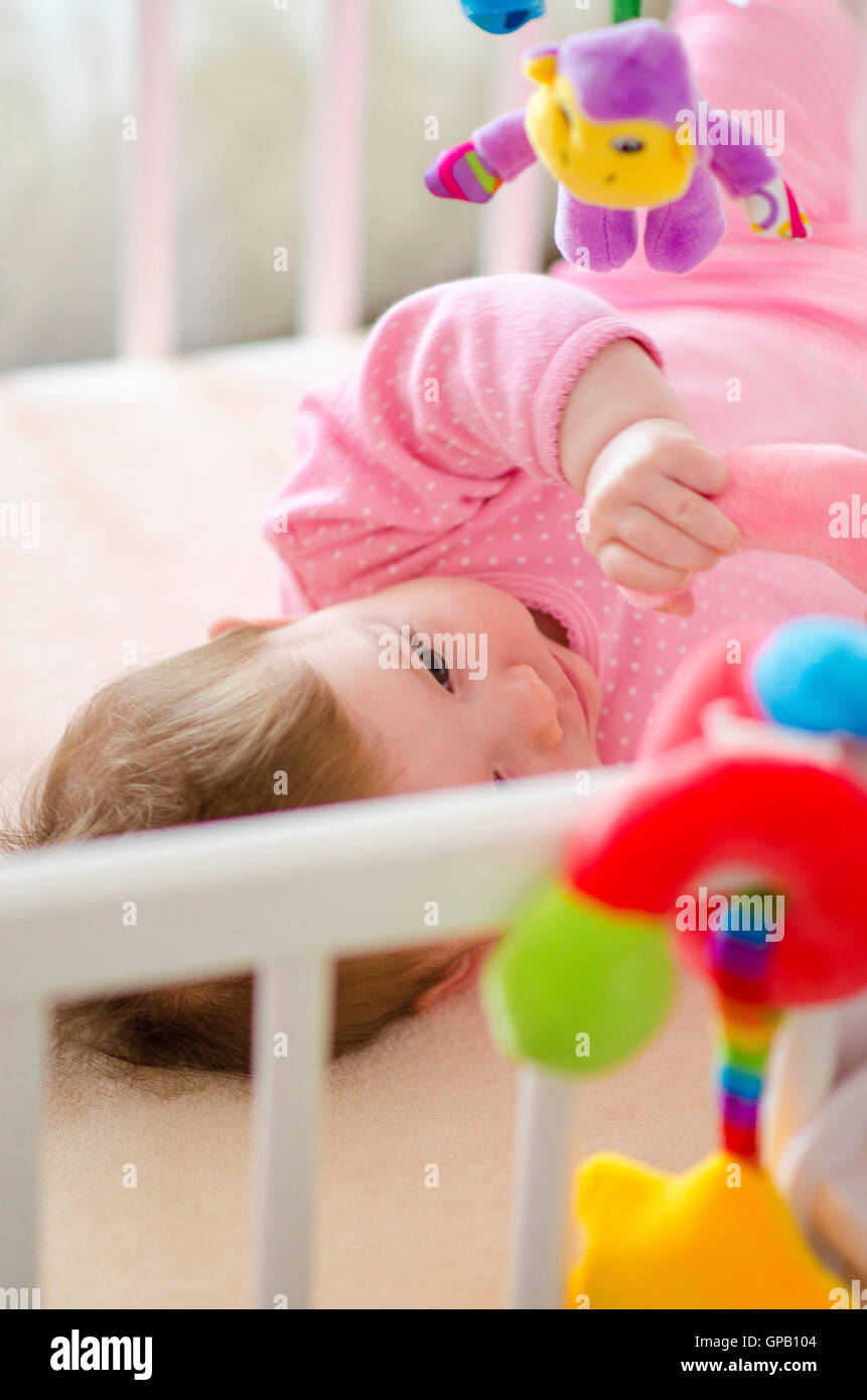 little cute baby girl playing in a cot Stock Photo - Alamy