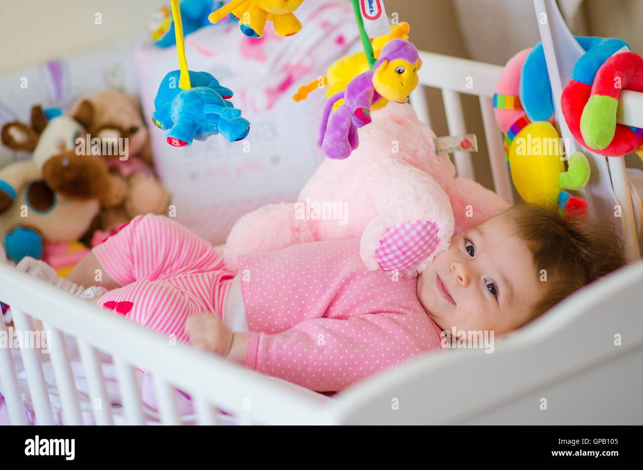 little cute baby girl playing in a cot Stock Photo - Alamy