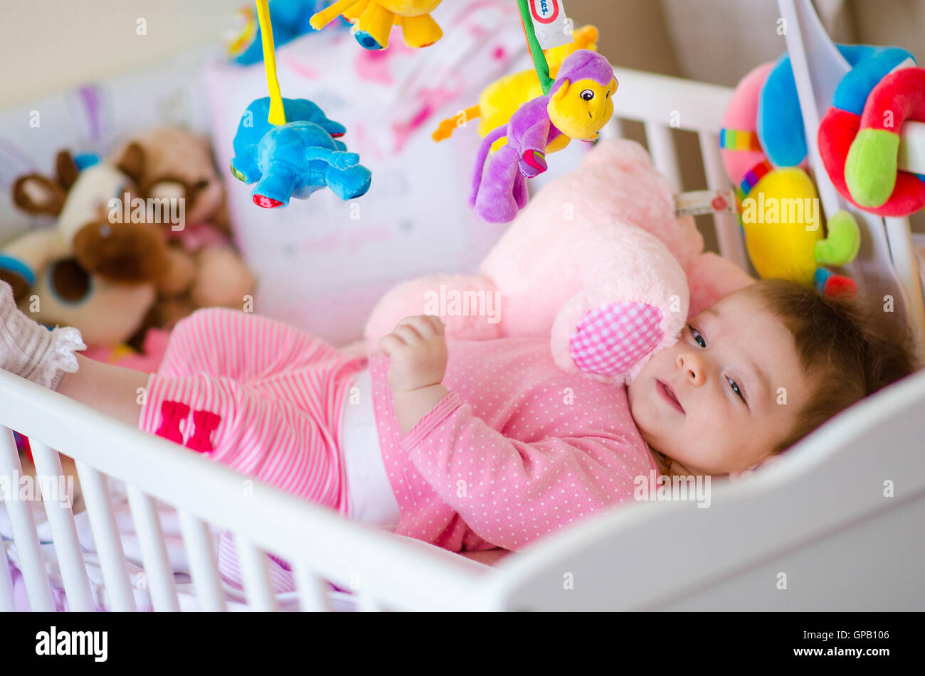 little cute baby girl playing in a cot Stock Photo - Alamy