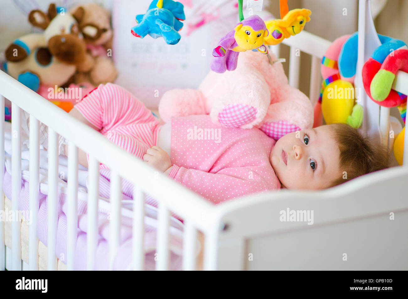 little cute baby girl playing in a cot Stock Photo - Alamy