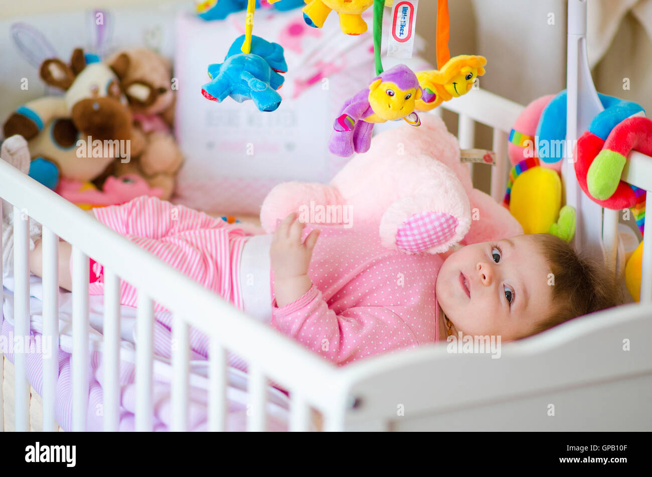 little cute baby girl playing in a cot Stock Photo - Alamy