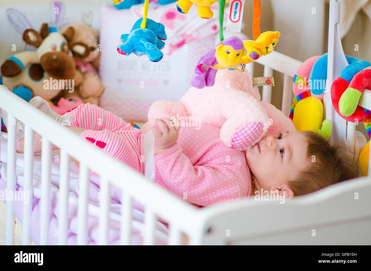 little cute baby girl playing in a cot Stock Photo - Alamy