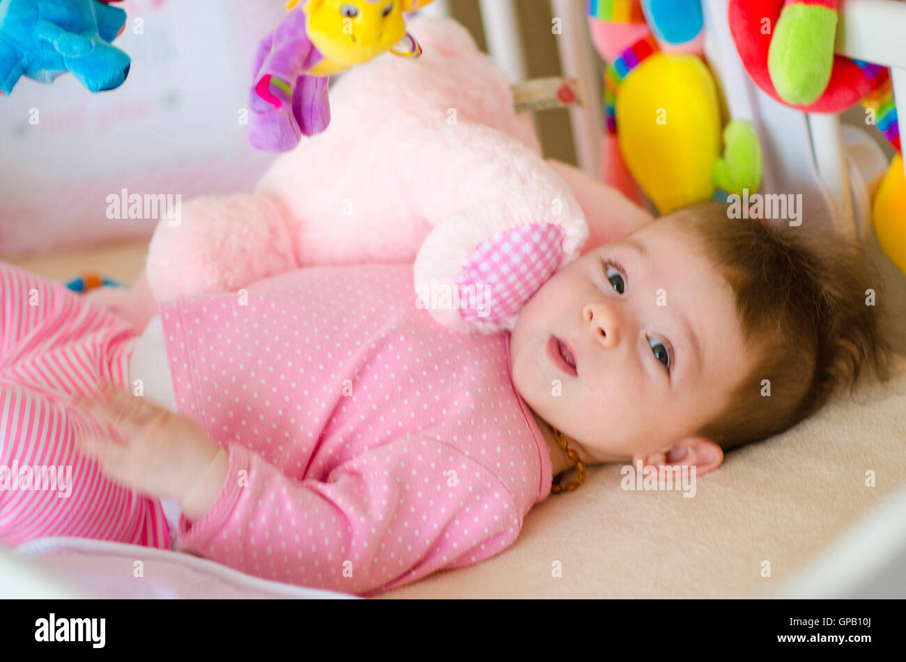 little cute baby girl playing in a cot Stock Photo - Alamy