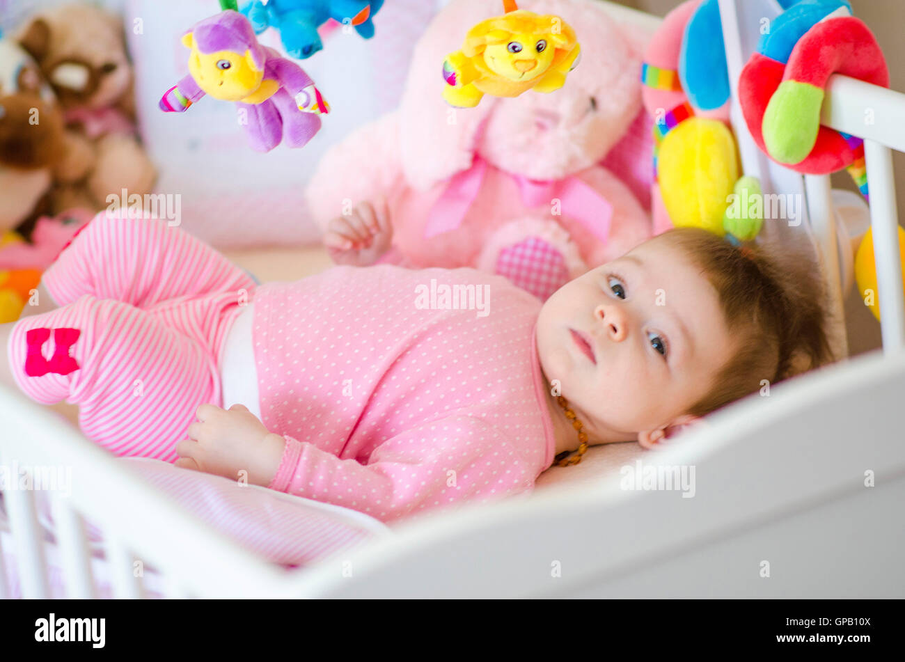 little cute baby girl playing in a cot Stock Photo - Alamy