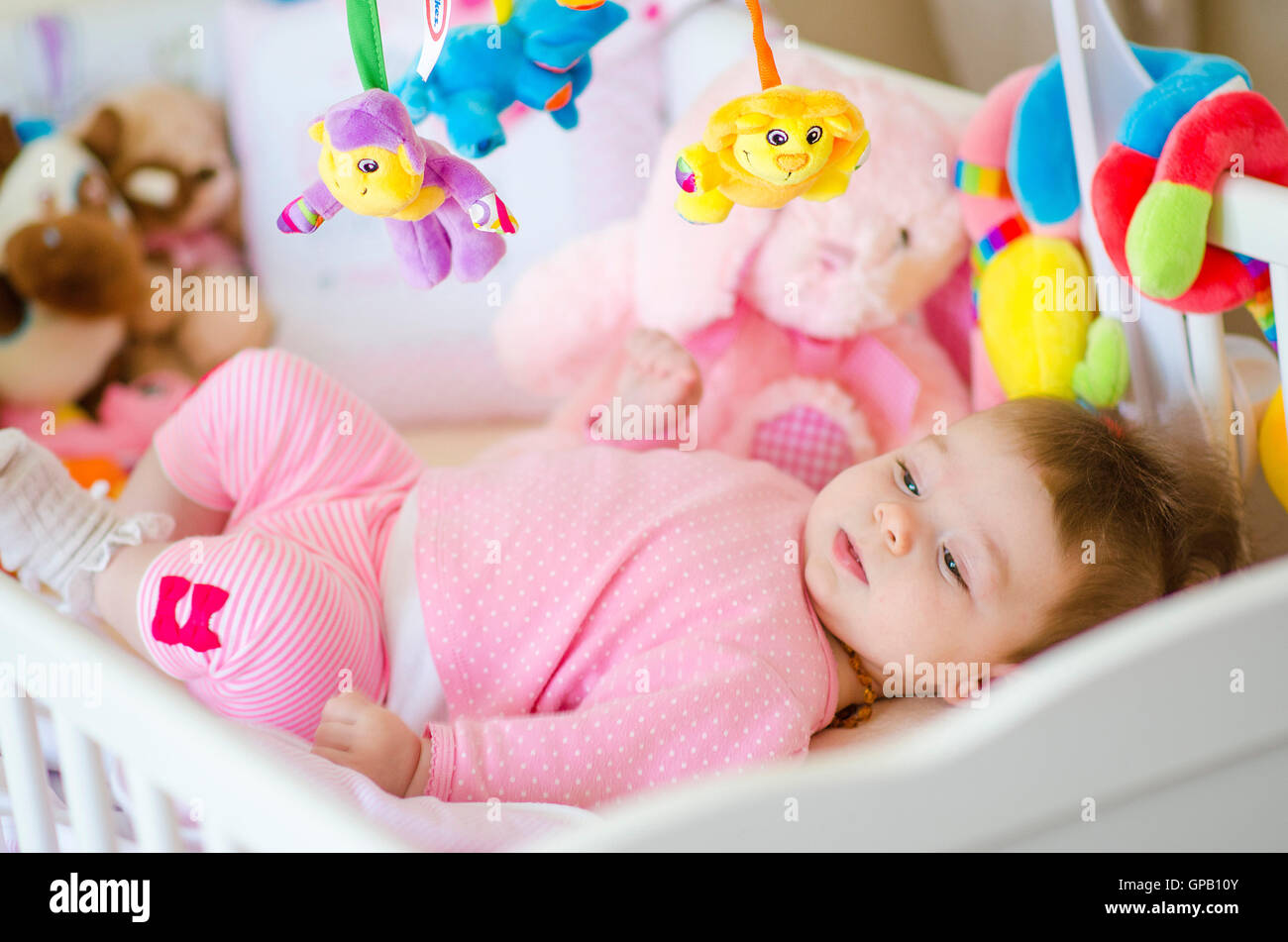 little cute baby girl playing in a cot Stock Photo - Alamy