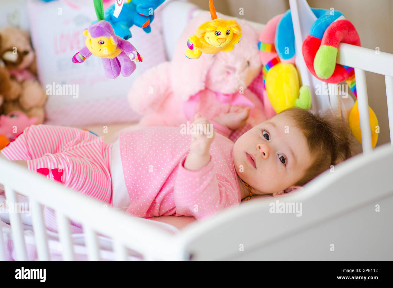 little cute baby girl playing in a cot Stock Photo - Alamy