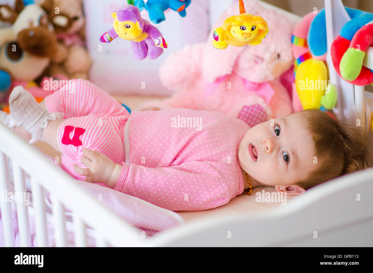 little cute baby girl playing in a cot Stock Photo - Alamy