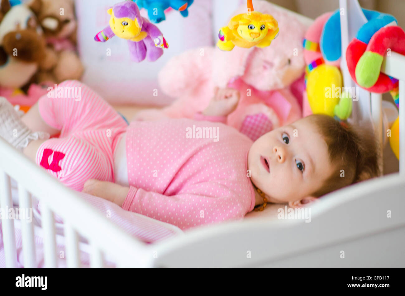 little cute baby girl playing in a cot Stock Photo - Alamy